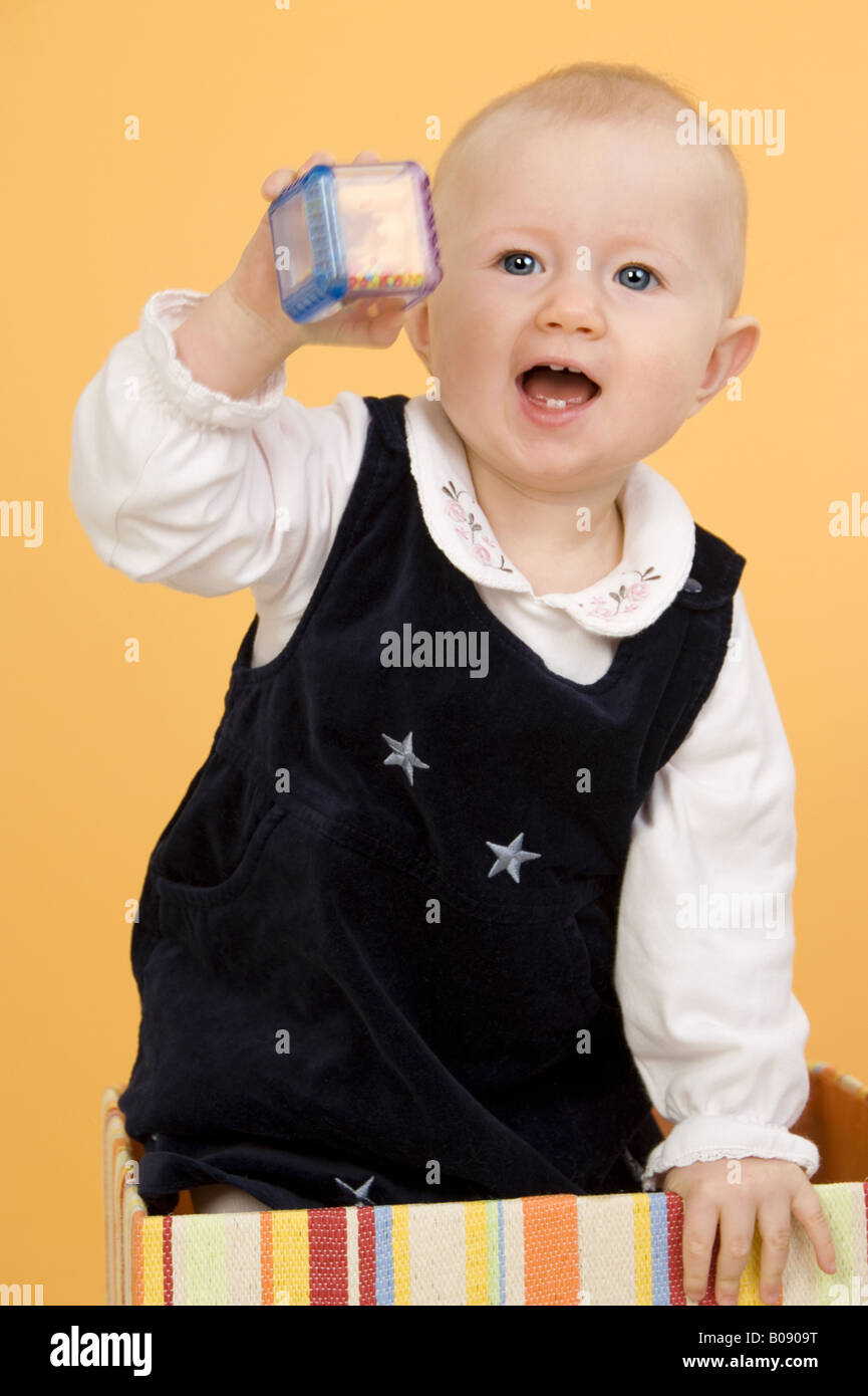 baby with rattle standing in a box Stock Photo - Alamy
