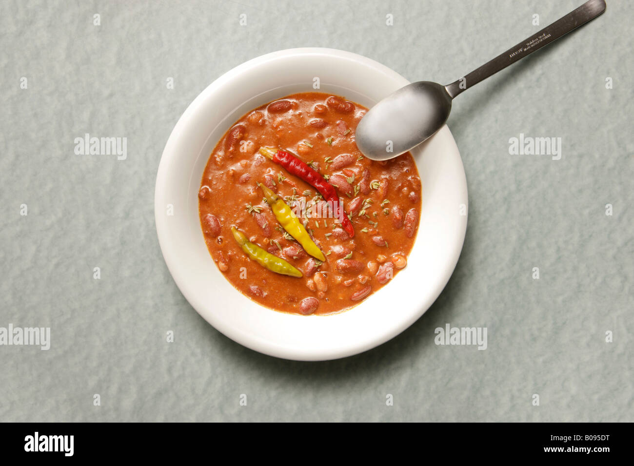 Spoon beside chili con carne garnished with hot chili peppers on a ...