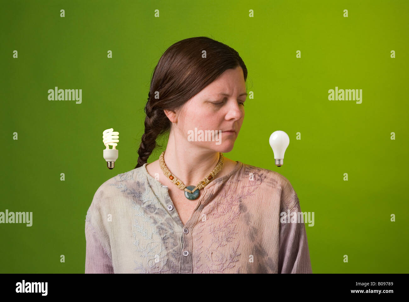 an environmentalist looks disdainfully at an incandescent light bulb ...