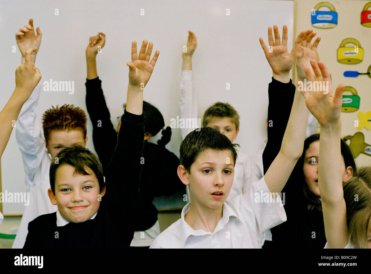 Primary school pupils,hands up in class Stock Photo - Alamy