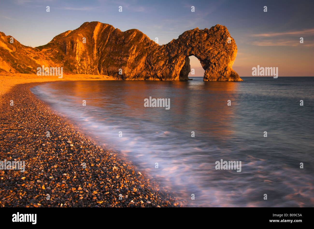 Golden sunlight catches the natural rock arch at Durdle Door in Dorset ...