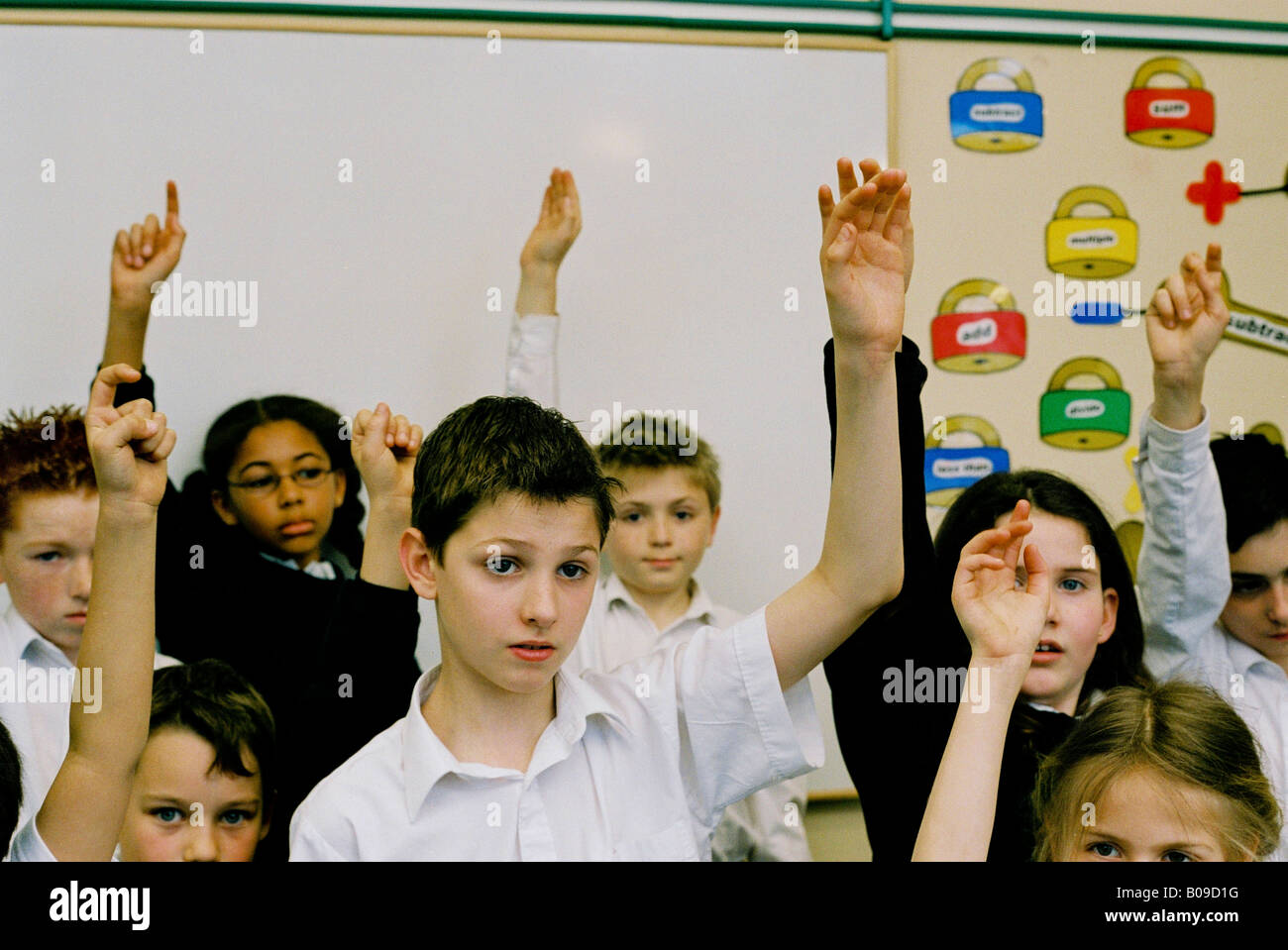 Primary school pupils,hands up in class Stock Photo - Alamy