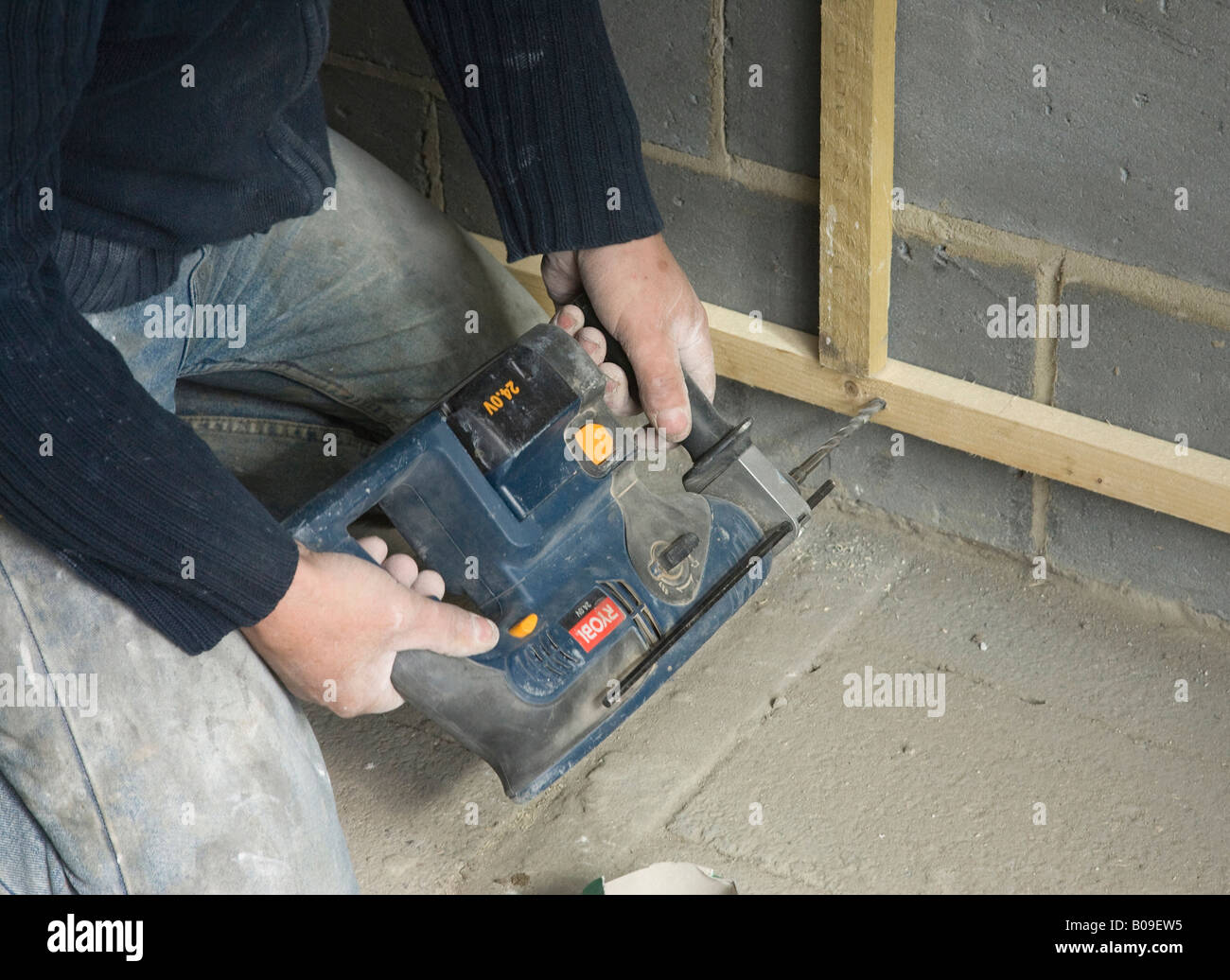 builder with drill fitting battens to an internal wall Stock Photo - Alamy
