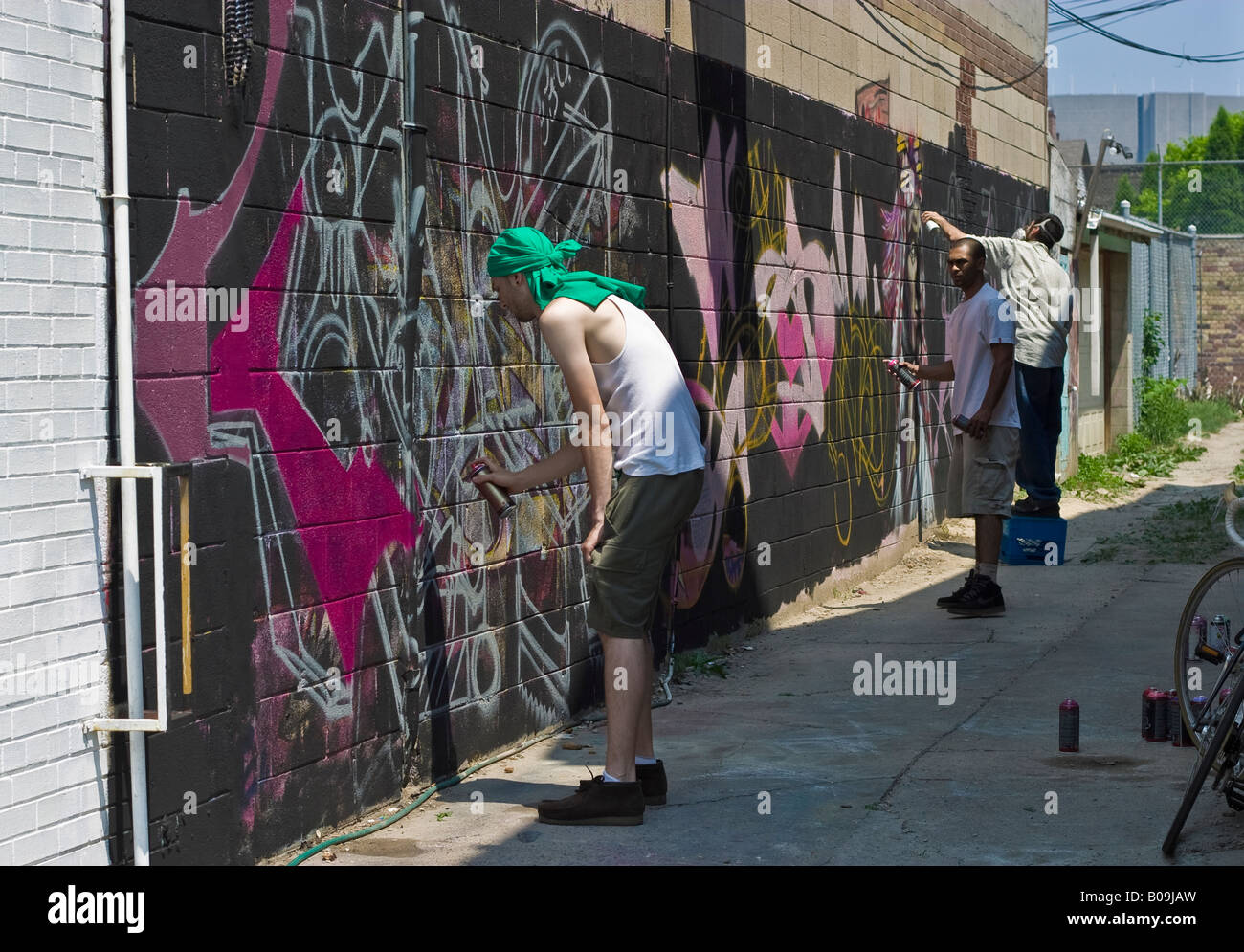 Young men spray painting a wall grafitti Stock Photo - Alamy