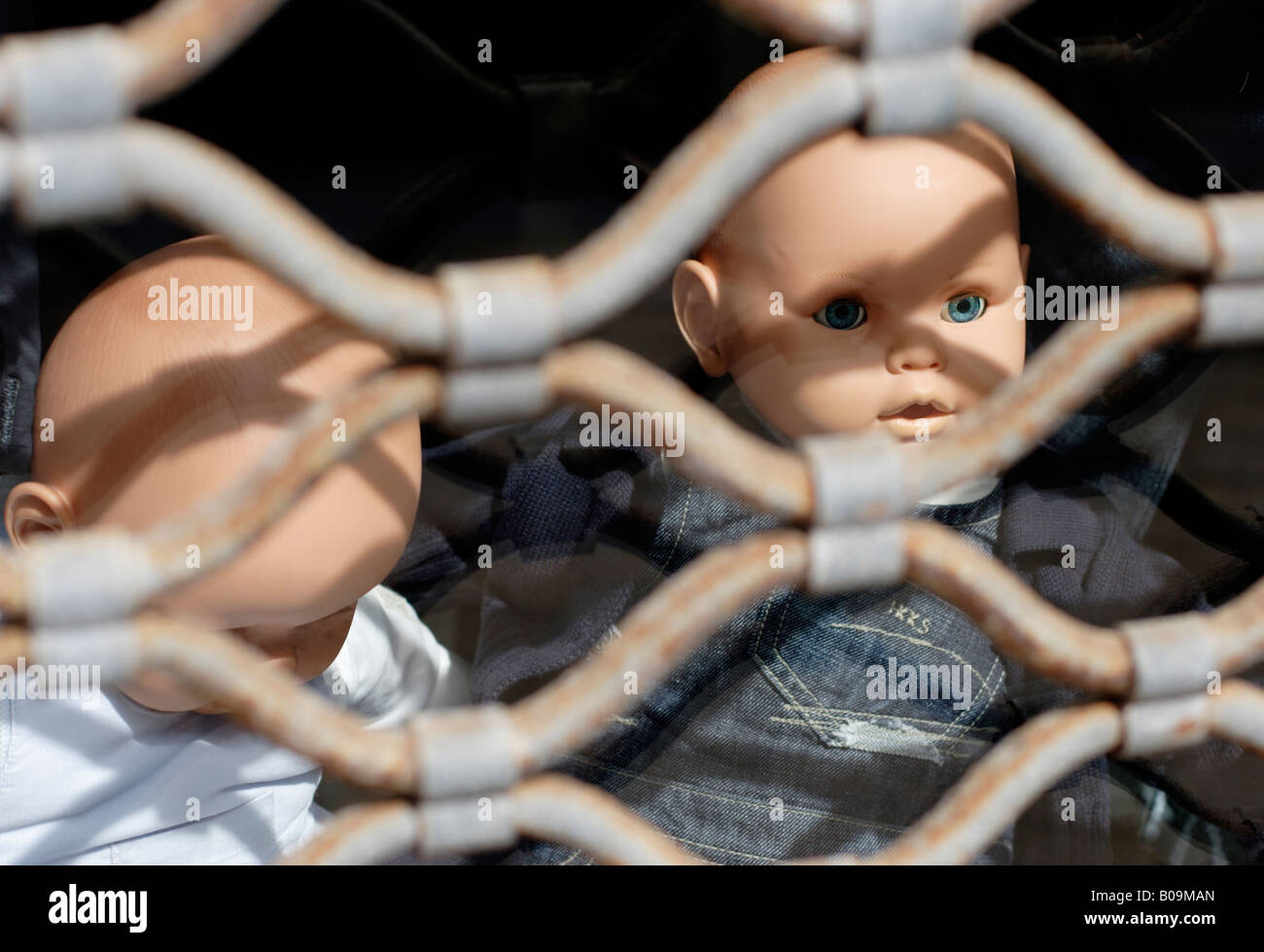 Two dolls trapped behind a metal shop window grill Stock Photo - Alamy