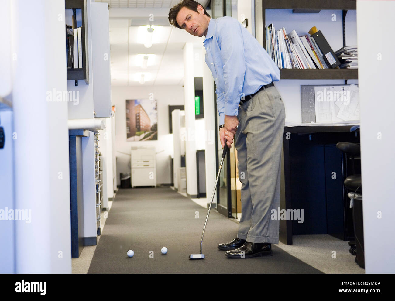 Businessman playing golf in office Stock Photo - Alamy