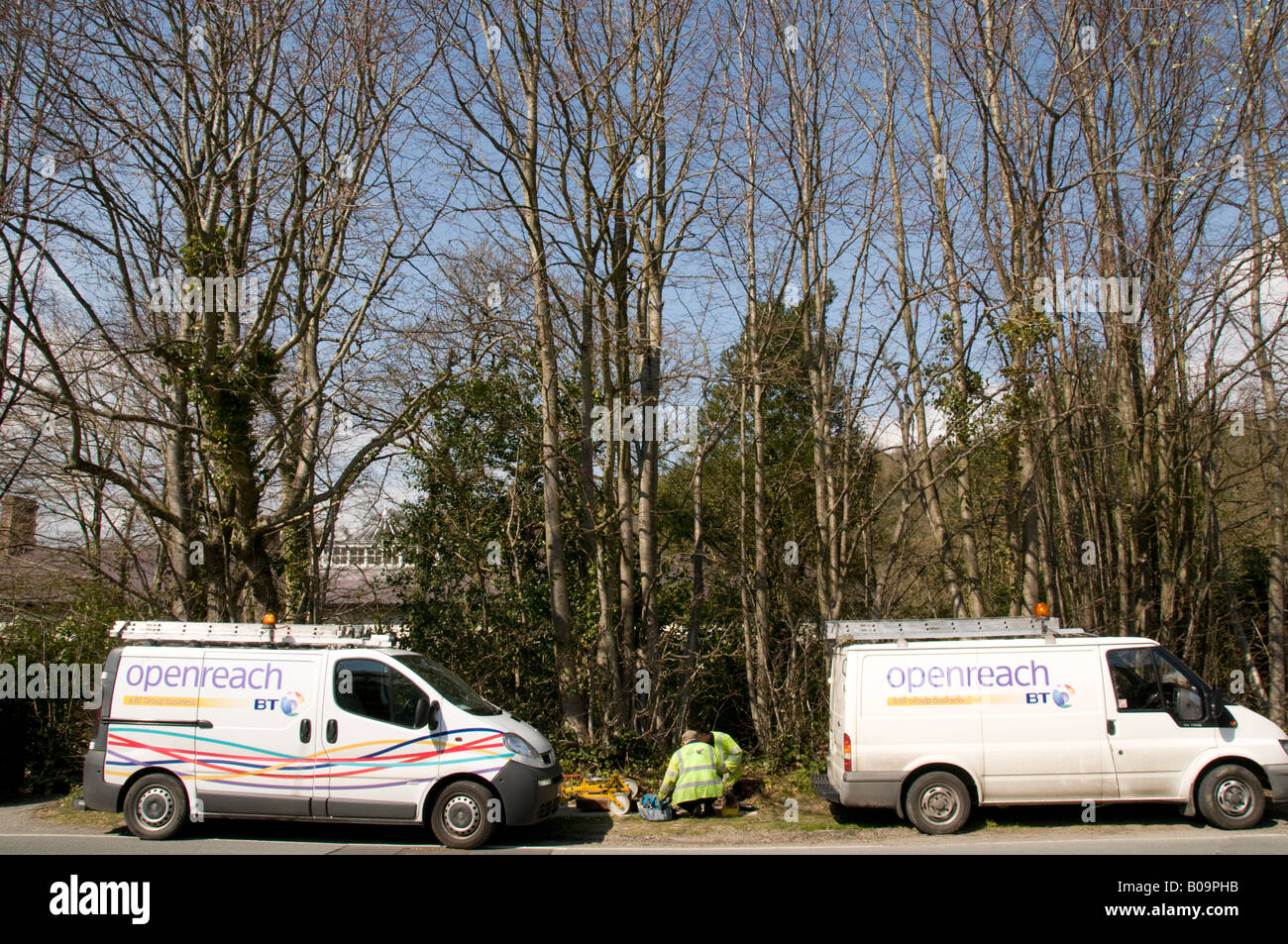 Two BT openreach vans with telephone engineers in between kneeling on ...