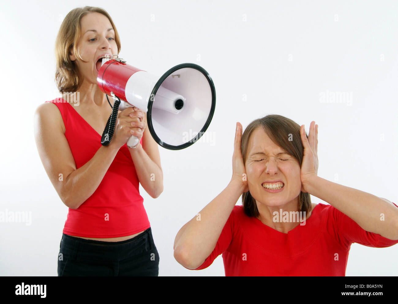 woman screaming in megaphone, other woman keeps shut ears Stock Photo ...