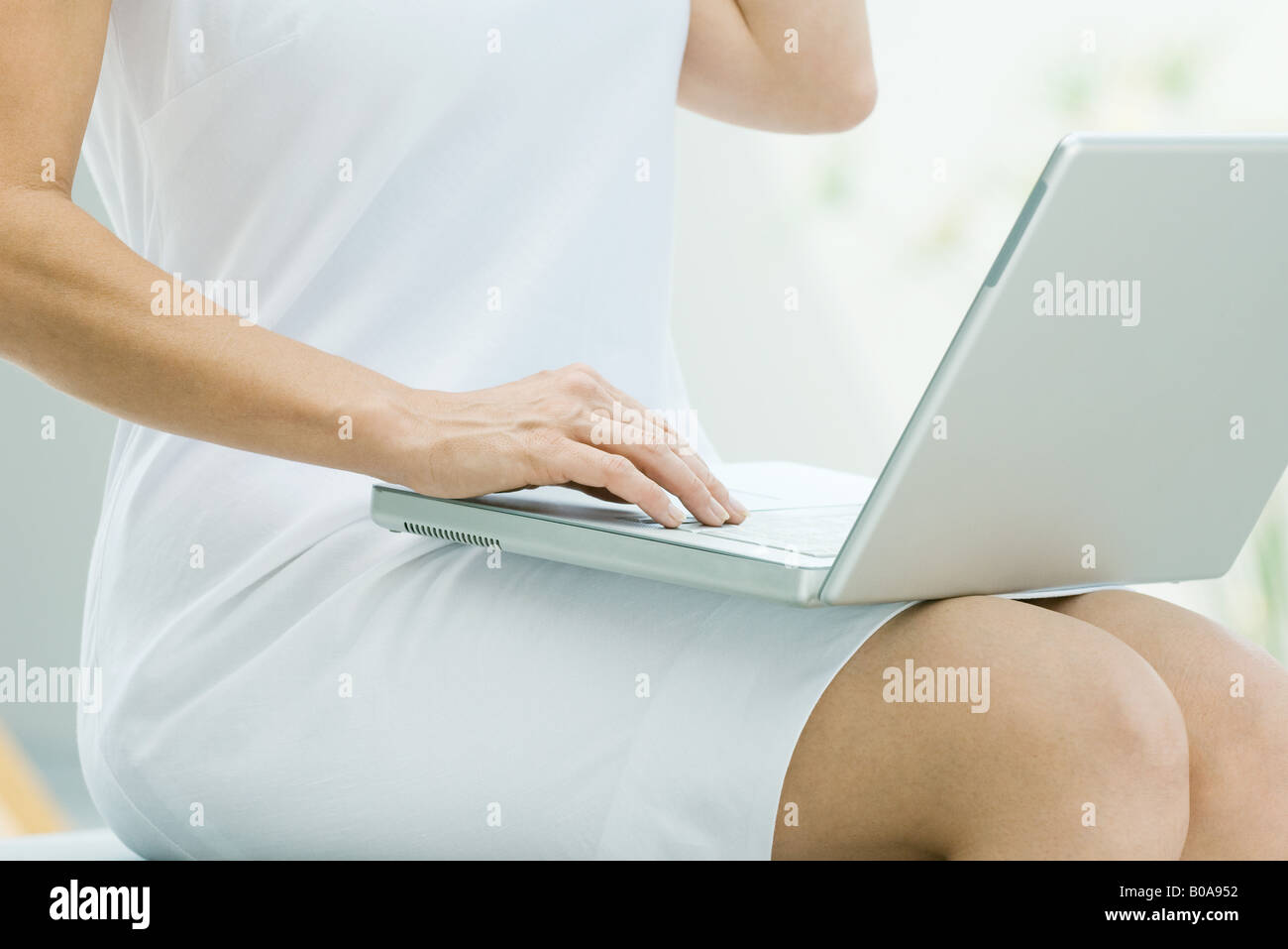 Woman sitting, using laptop computer, cropped view Stock Photo - Alamy