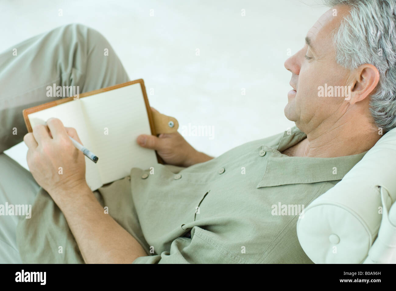 Mature man sitting, writing in diary, side view Stock Photo - Alamy