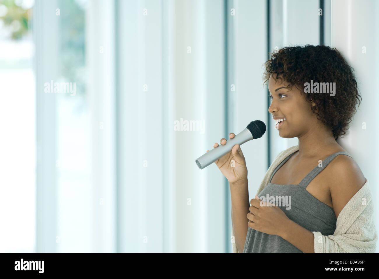 Young woman singing into microphone, looking away Stock Photo - Alamy