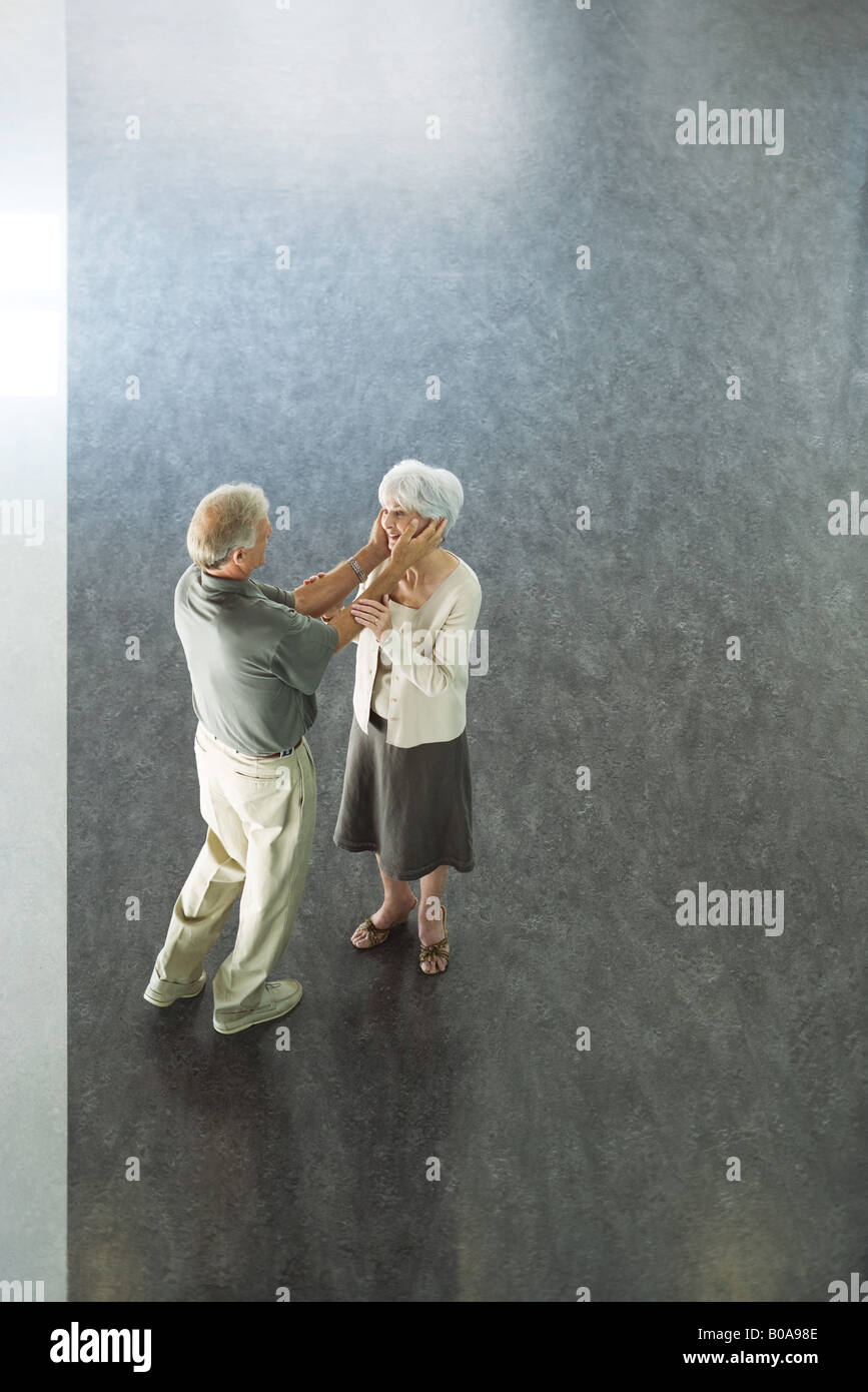 Couple standing face to face, man holding woman's face in hands, high ...