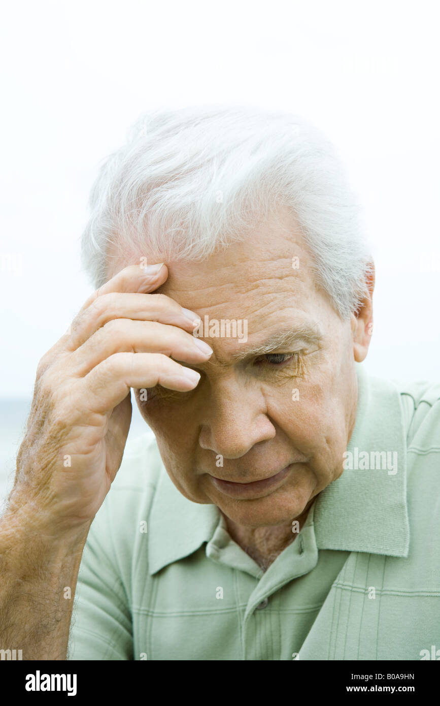 Senior man holding head, looking down, close-up Stock Photo - Alamy