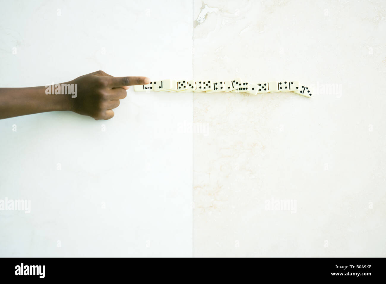 Child knocking over line of dominoes, cropped view of hand Stock Photo ...
