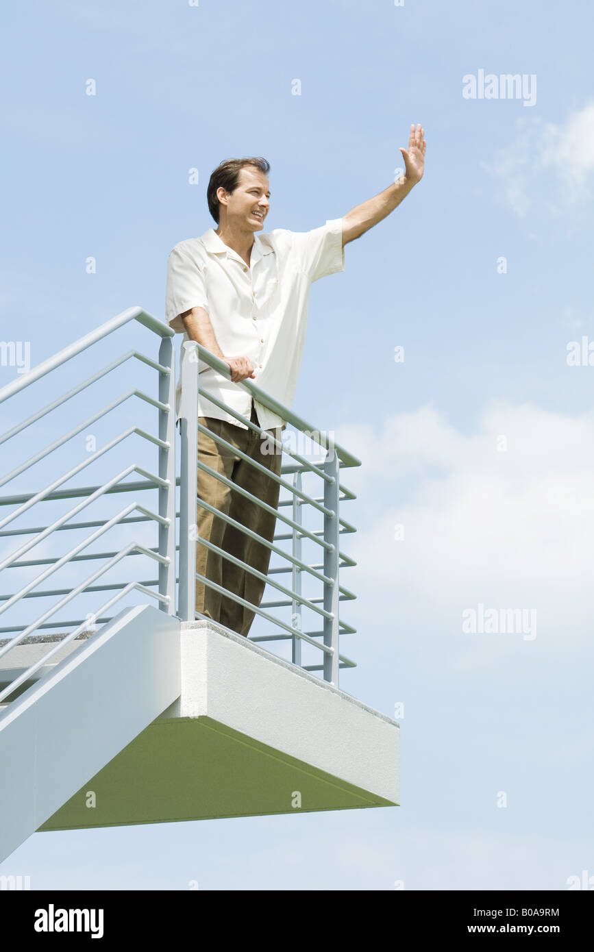 Man leaning against railing, waving, low angle view Stock Photo - Alamy