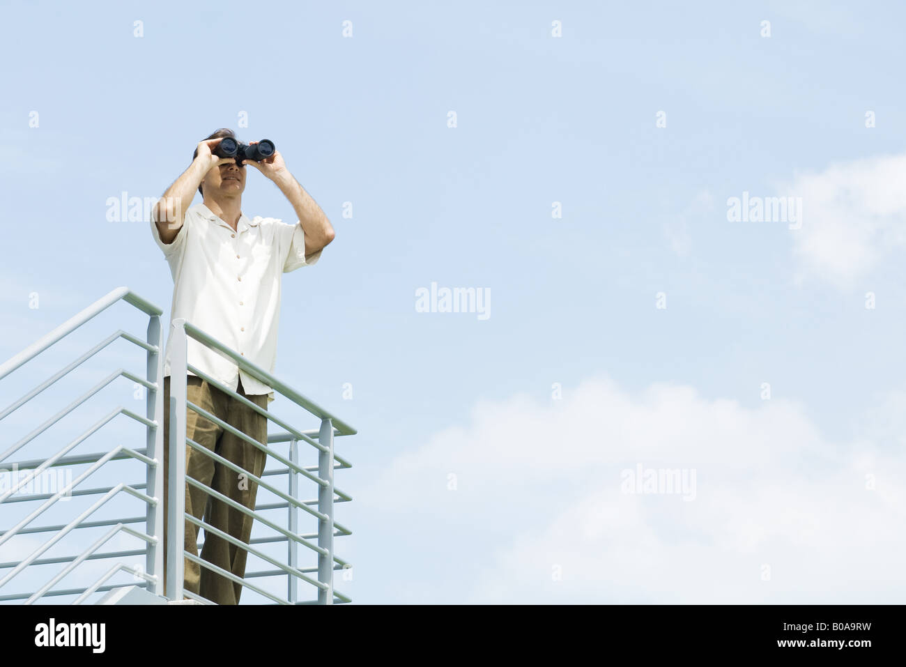 Man looking through binoculars Stock Photo - Alamy