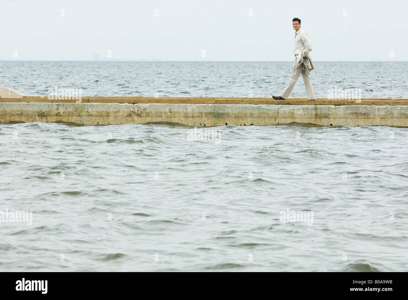 Man walking on jetty, looking toward camera Stock Photo - Alamy