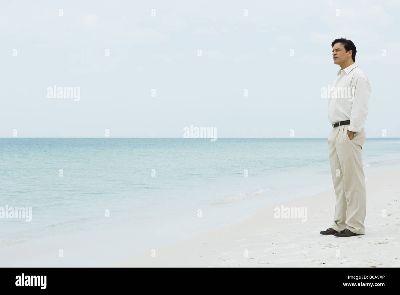 Man standing on beach, looking at view Stock Photo - Alamy