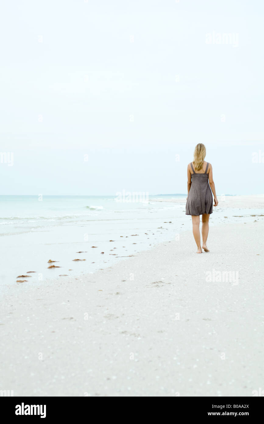 Woman in sundress walking at the beach, rear view Stock Photo - Alamy