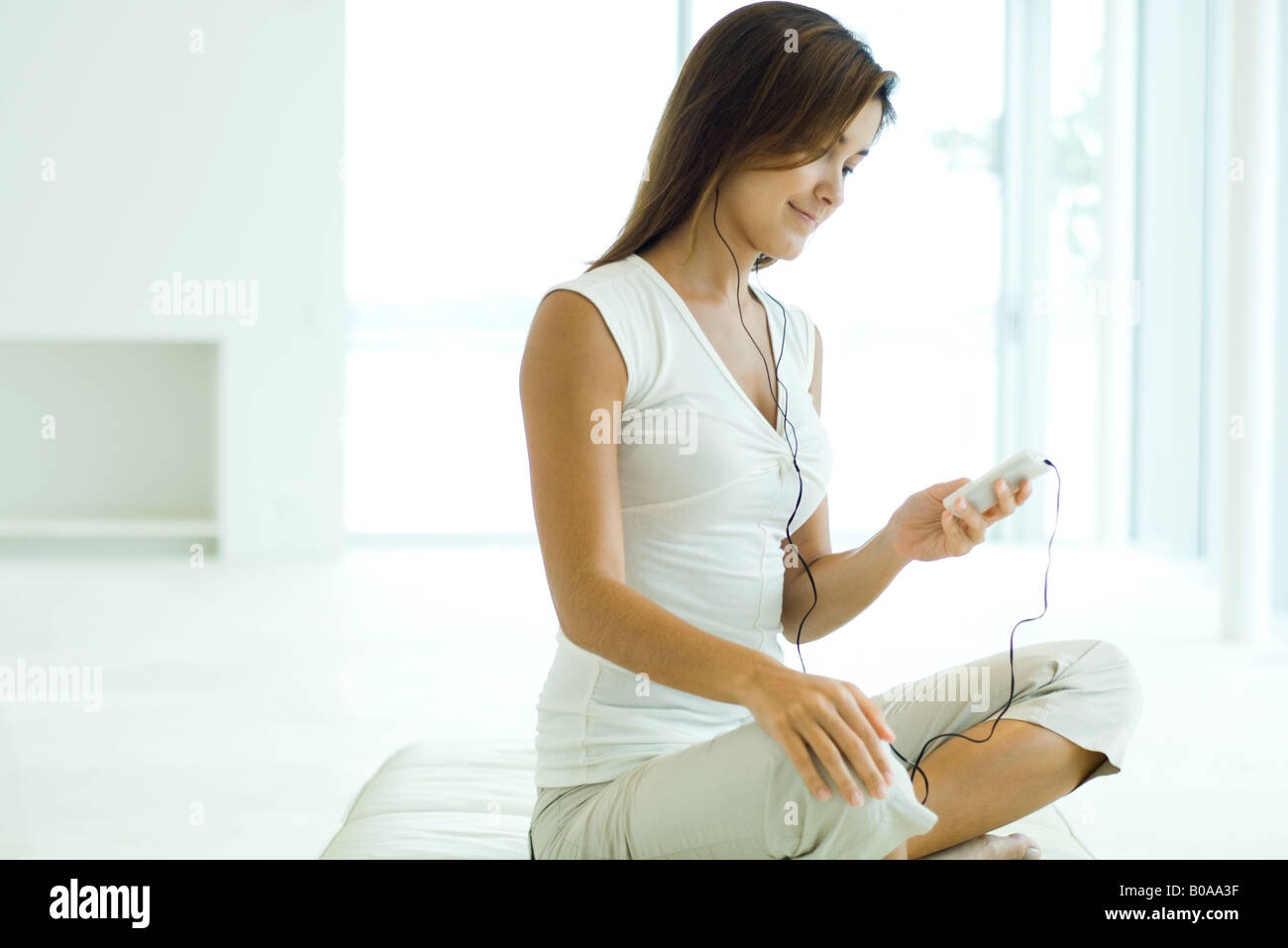 Young woman sitting cross-legged, listening to mp3 player Stock Photo ...