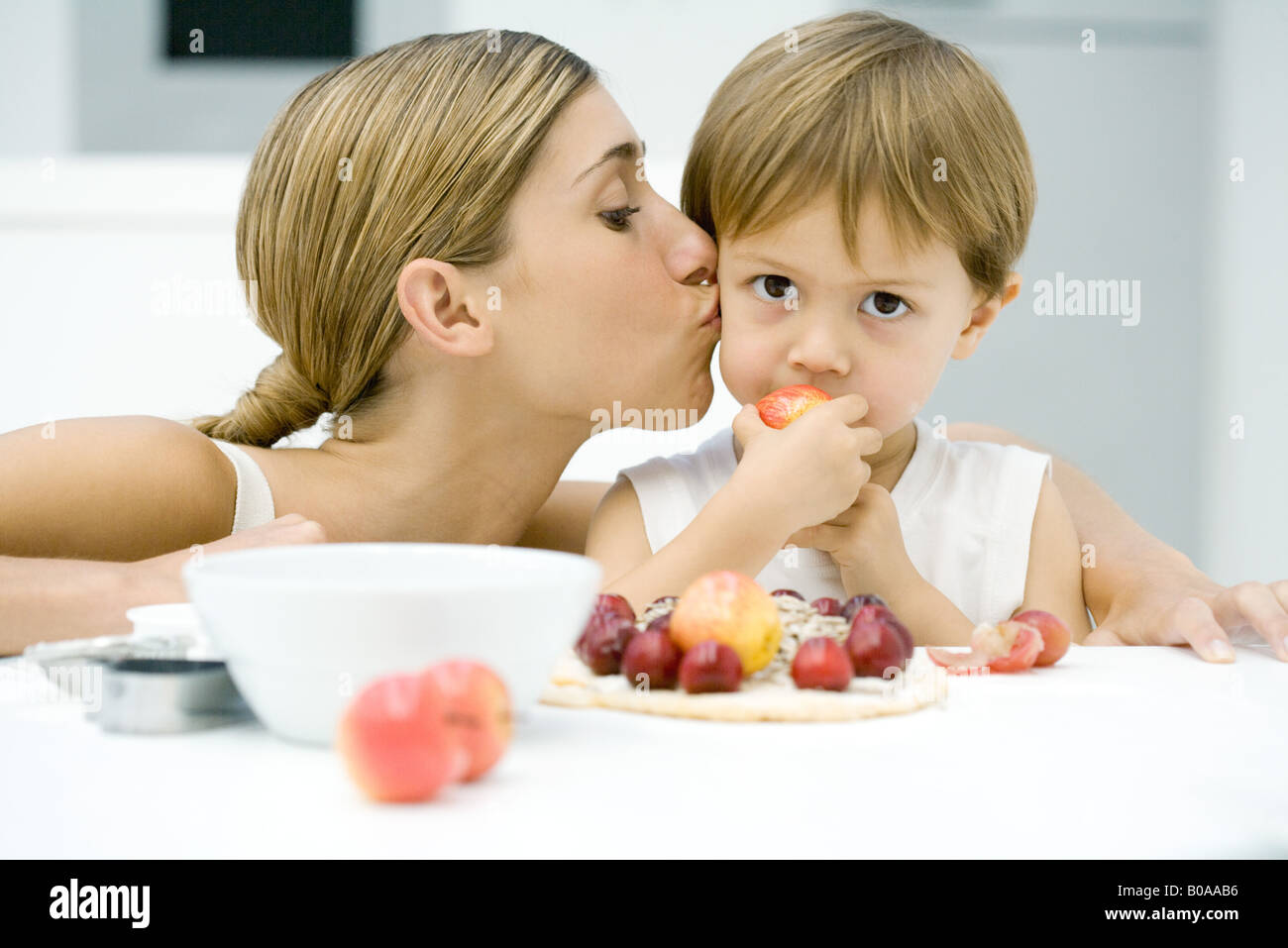 Woman kissing little boy on cheek, boy eating apple Stock Photo - Alamy