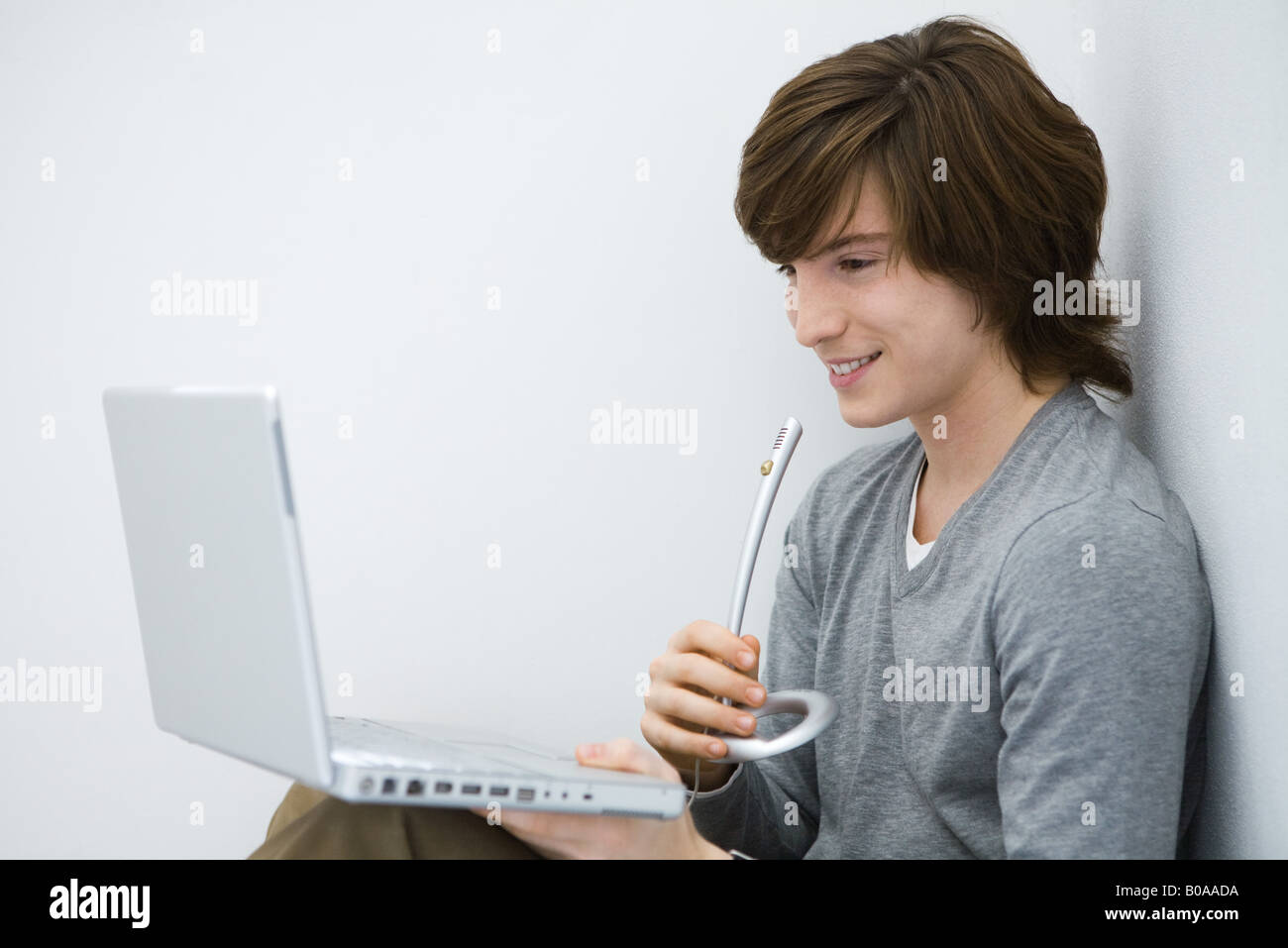 Young man looking at laptop computer, speaking into microphone, side ...