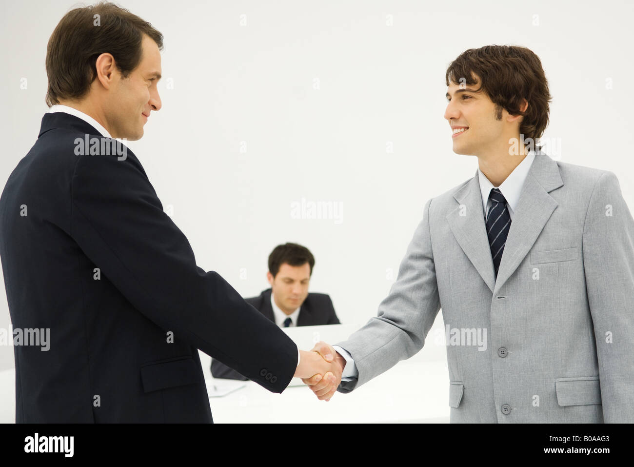 Two businessmen shaking hands, smiling at each other Stock Photo - Alamy