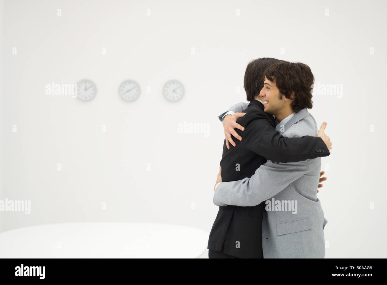 Two businessmen embracing, smiling, side view Stock Photo - Alamy