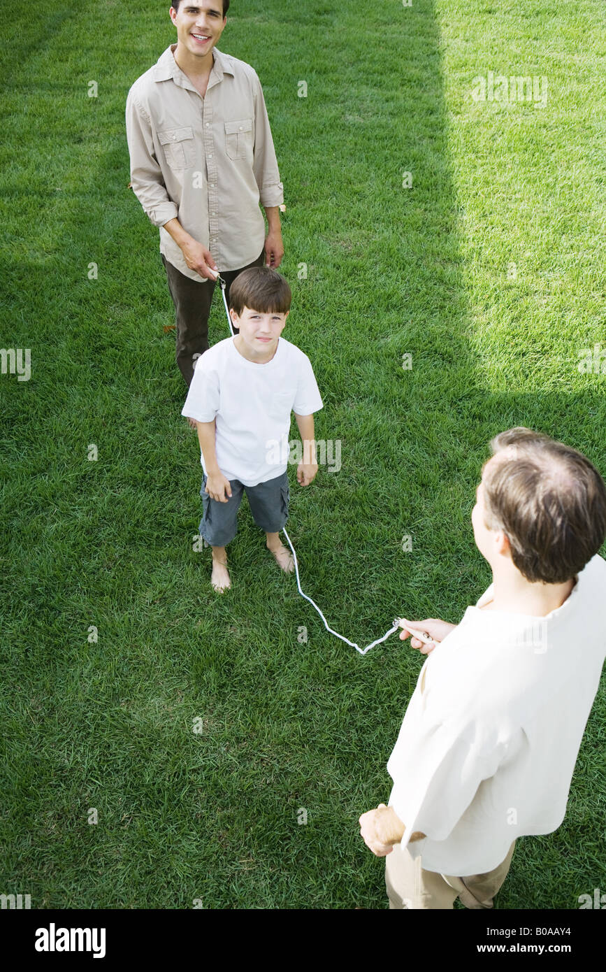 Boy playing jump rope with two men, smiling at camera Stock Photo - Alamy