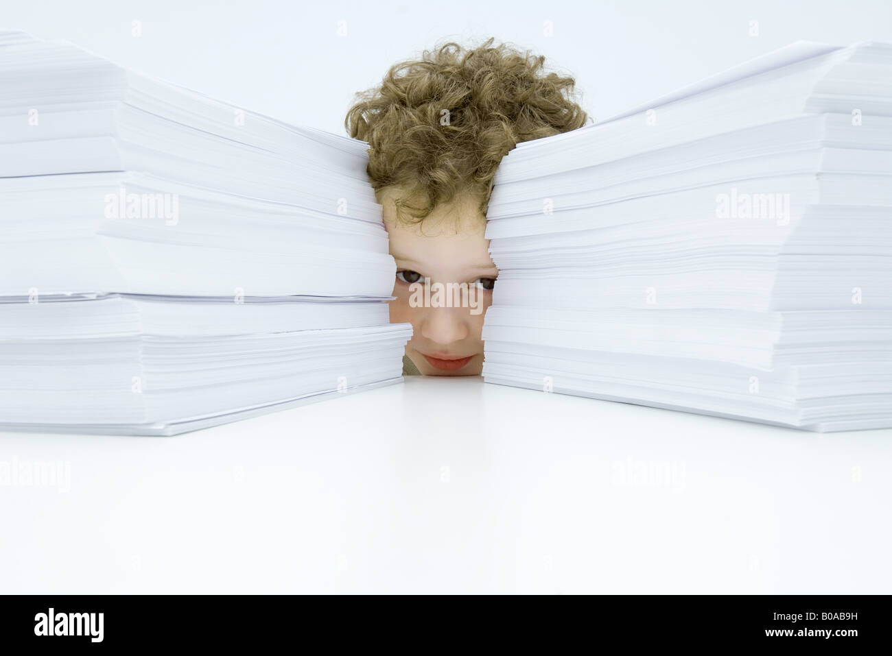 Little boy behind two large stacks of paper, peeking at camera Stock ...
