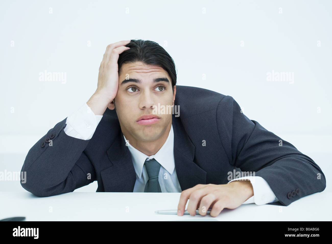 Young businessman slouching on desk, holding head Stock Photo - Alamy