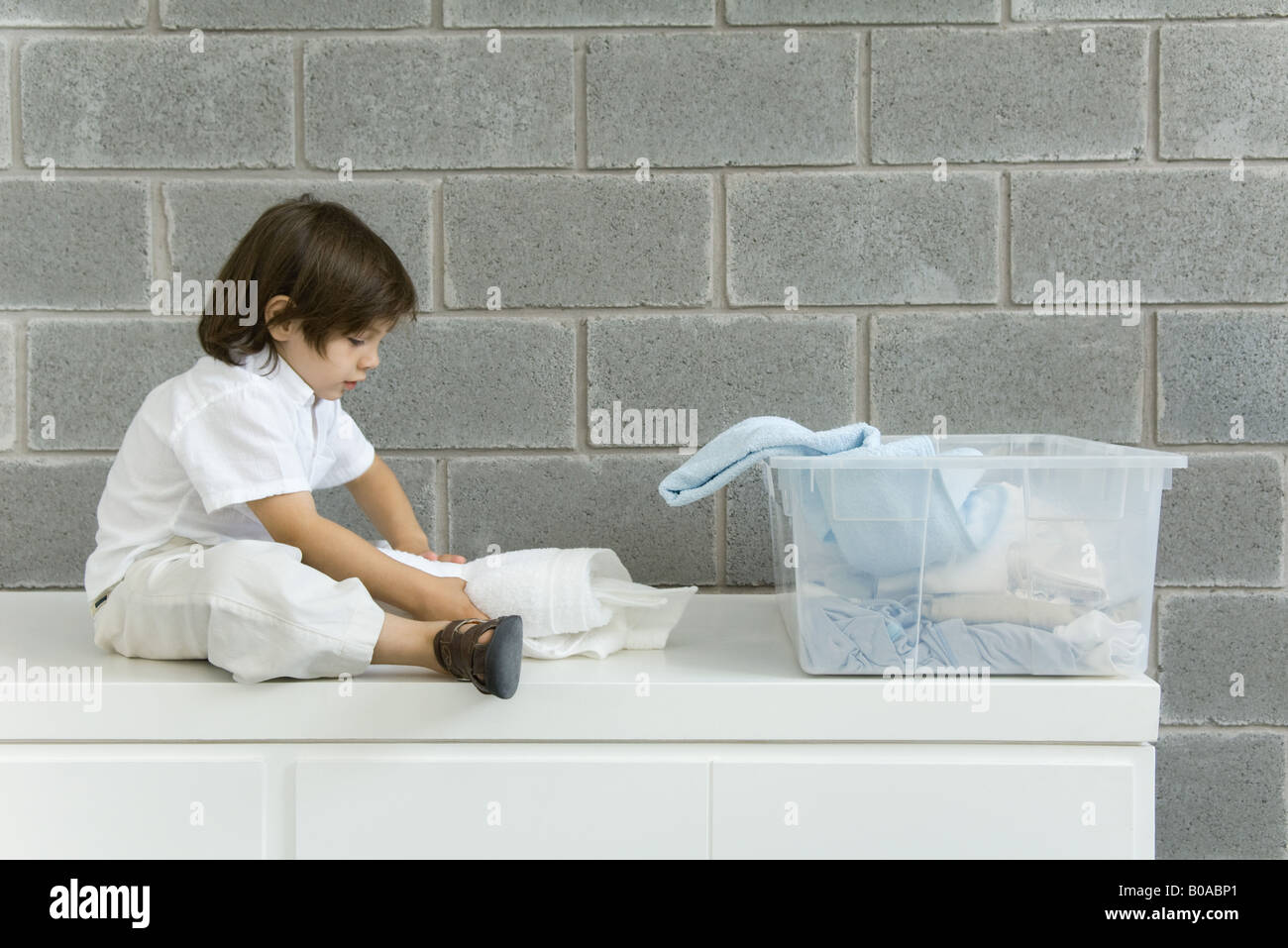 Little boy folding laundry, side view Stock Photo - Alamy