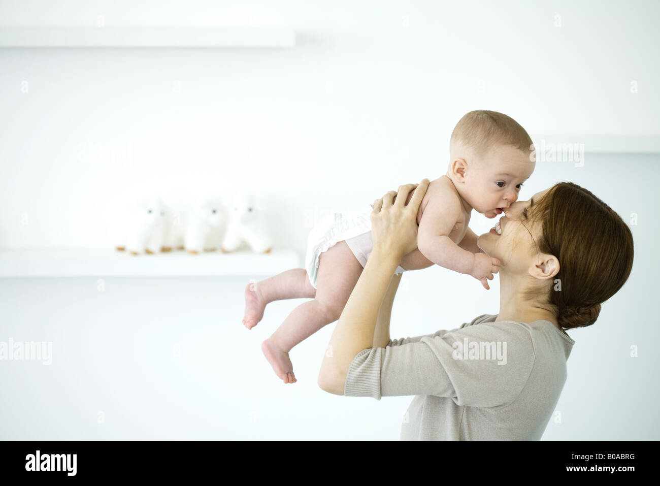 Mother holding baby up to face, smiling, side view Stock Photo - Alamy
