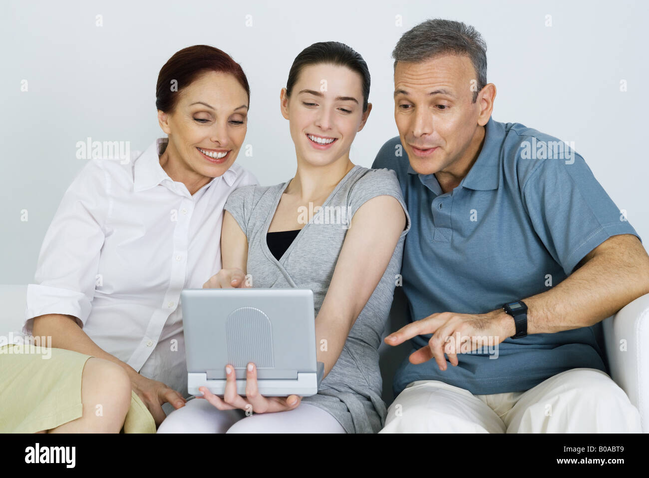 Teen girl watching portable DVD player with her parents, all smiling ...