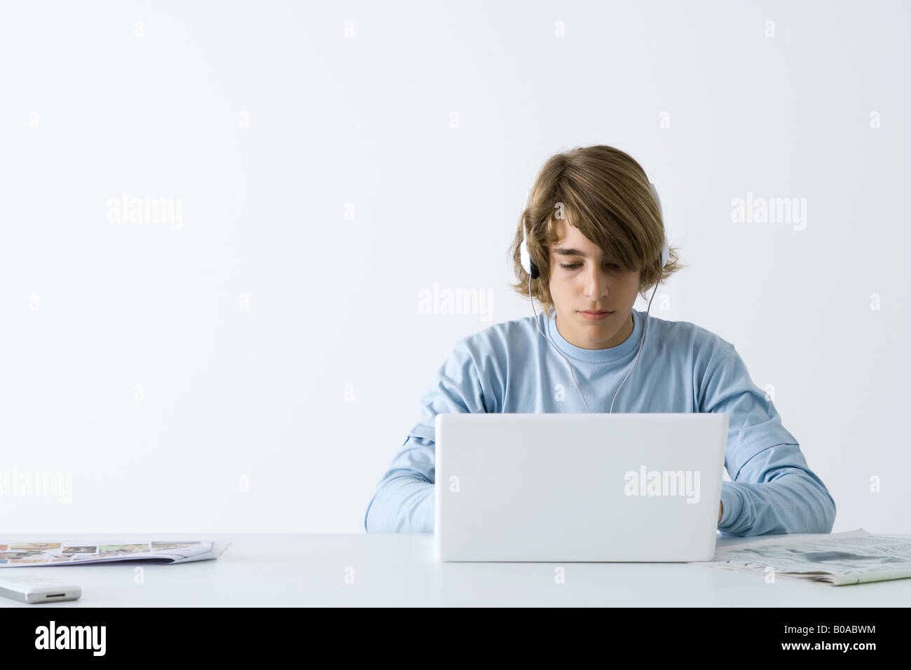 Teen boy using laptop computer, listening to headphones Stock Photo - Alamy