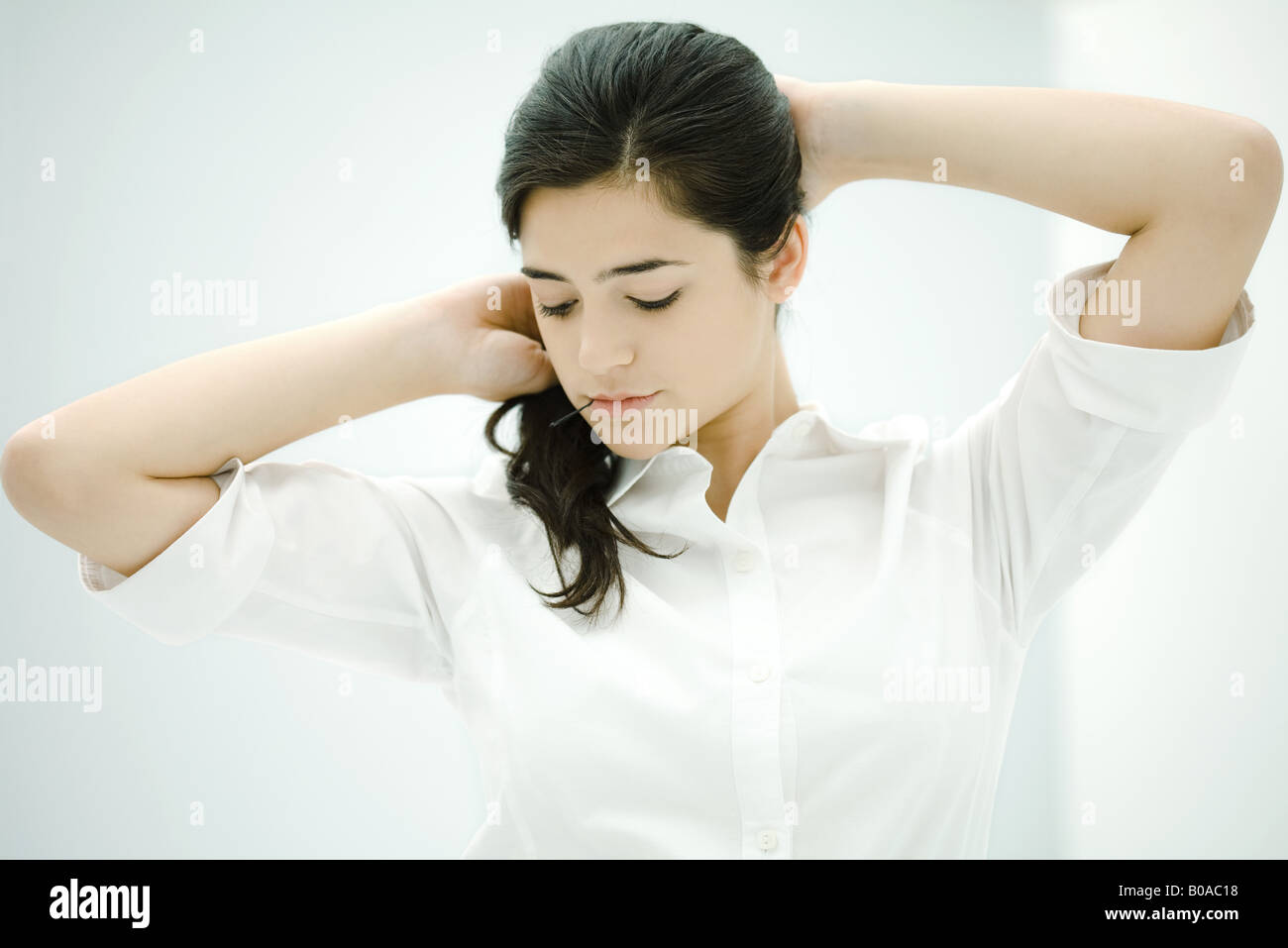 Woman fixing hair, holding hairpin in mouth, looking down Stock Photo ...