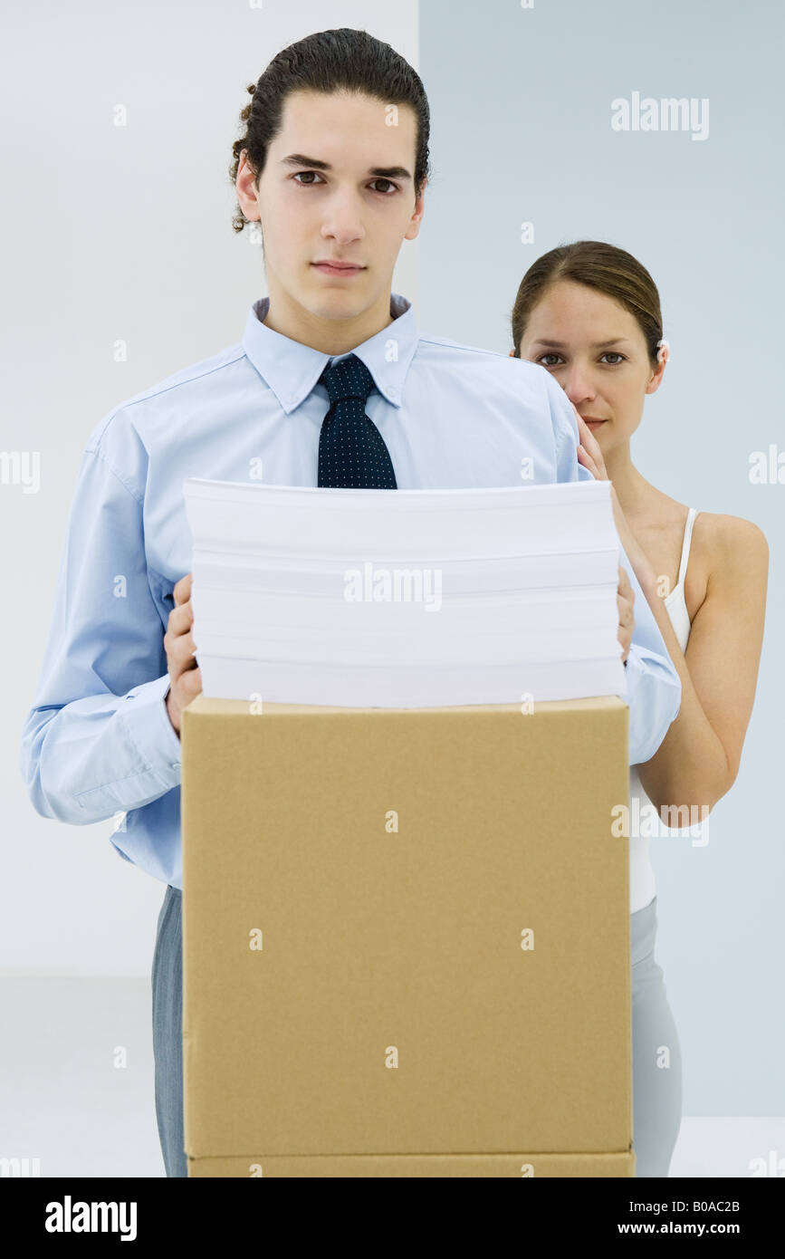 Young office workers, young man holding stack of paper on cardboard box ...