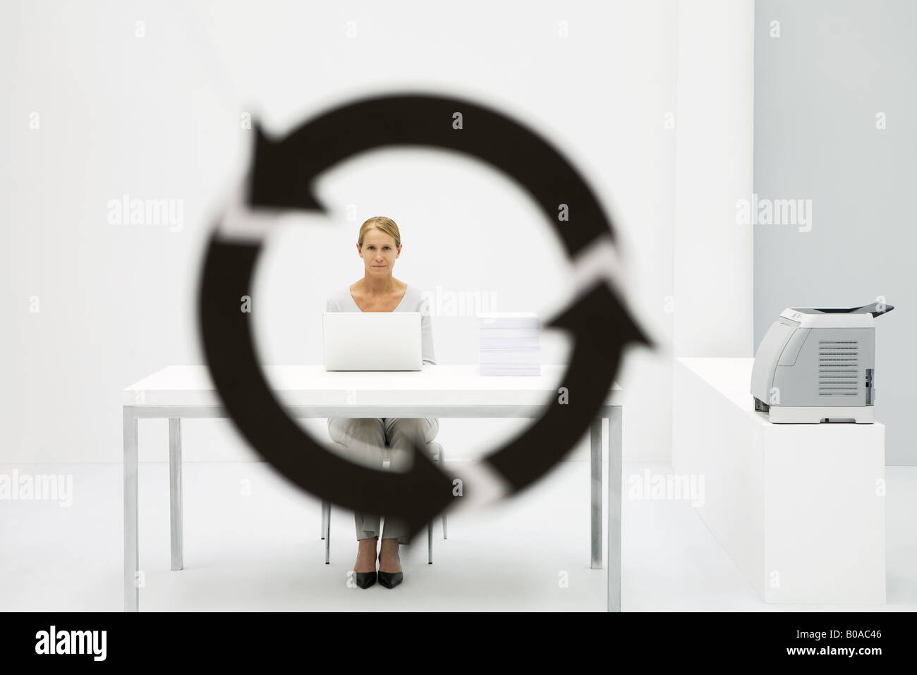 Female professional sitting in office, looking at camera through arrow ...