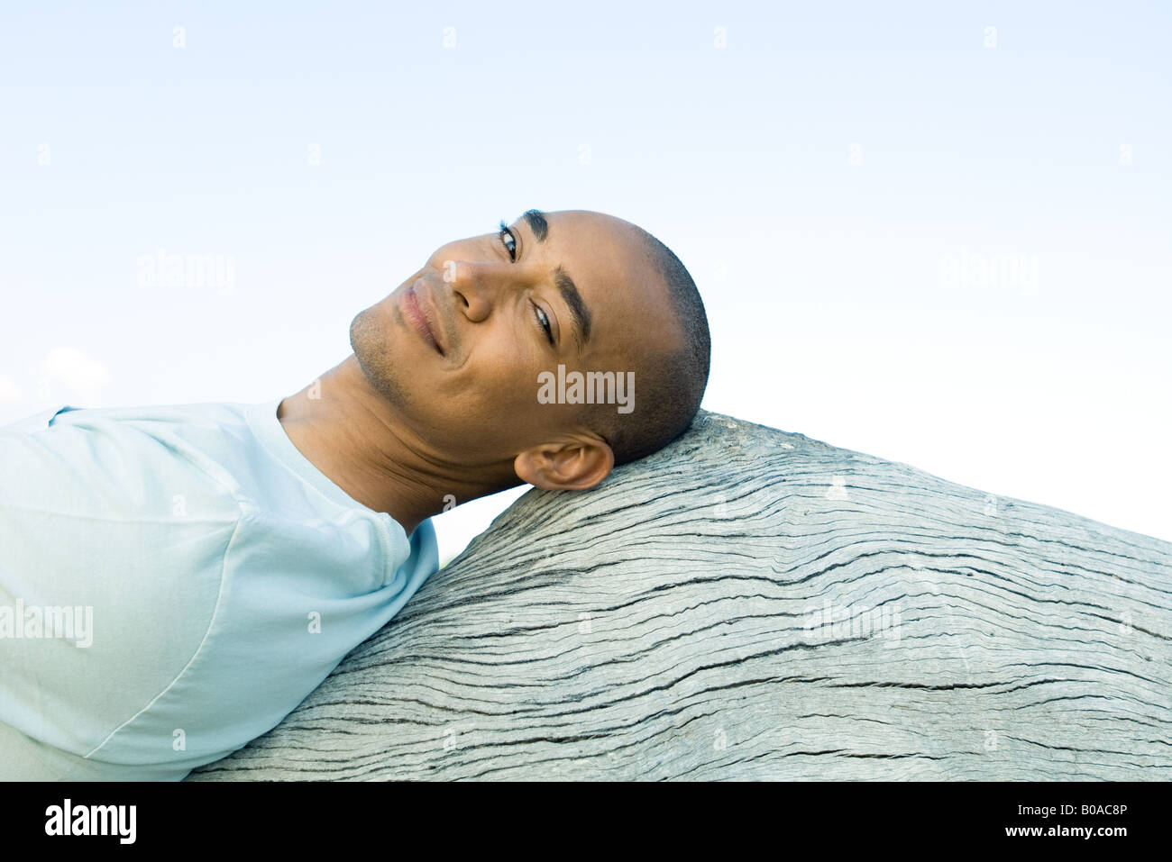 Man leaning back against wood surface, smiling at camera Stock Photo ...