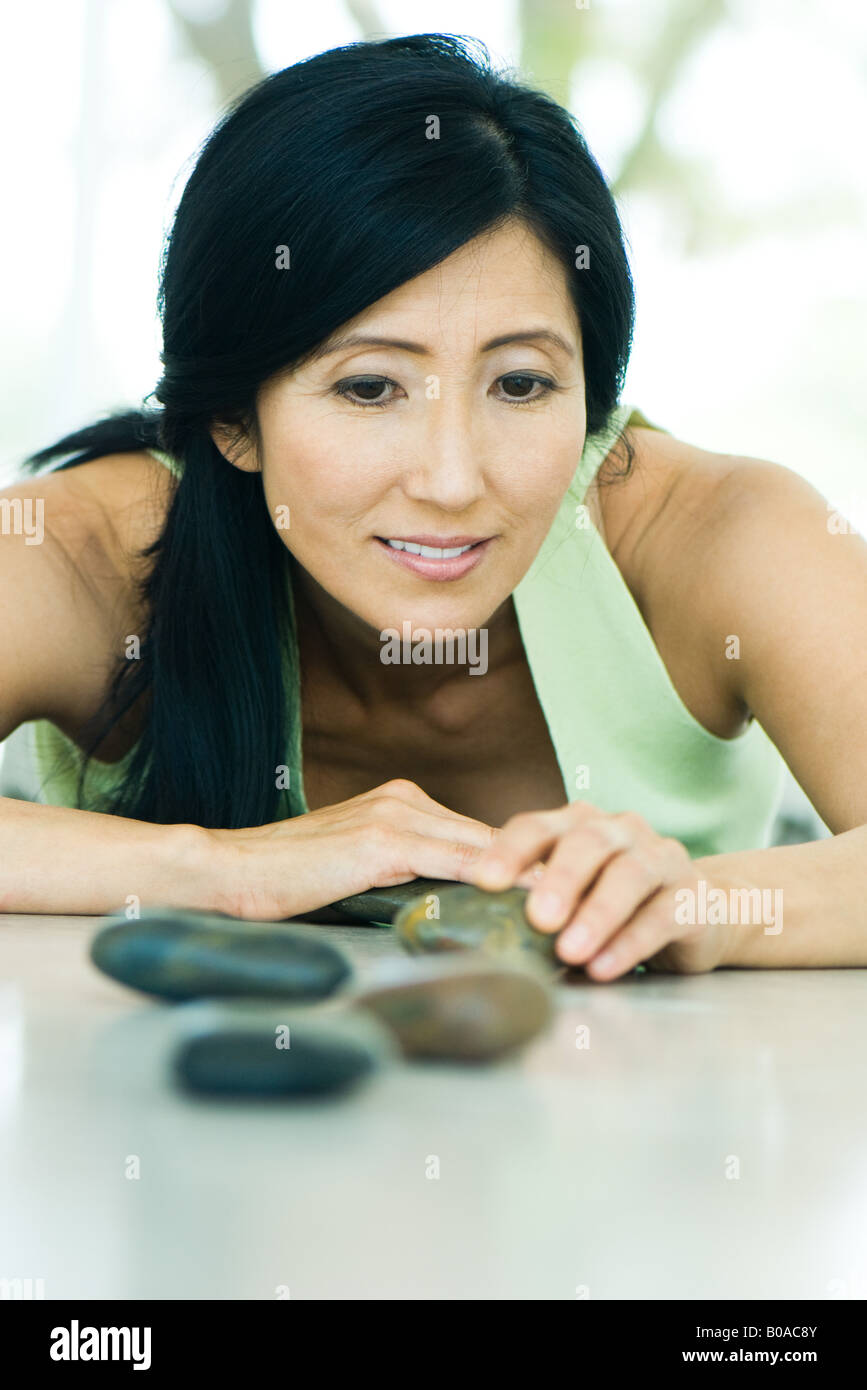 Woman leaning forward, arranging pebbles Stock Photo - Alamy