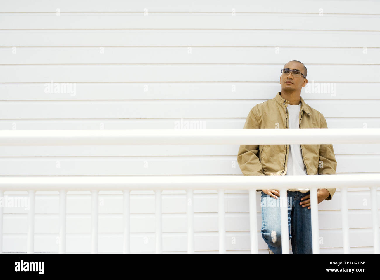 Man leaning against wall, hands on hips, looking away Stock Photo - Alamy