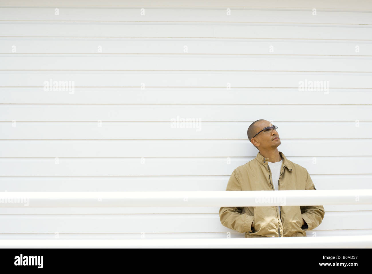 Man leaning against wall, hands in pockets, looking up Stock Photo - Alamy
