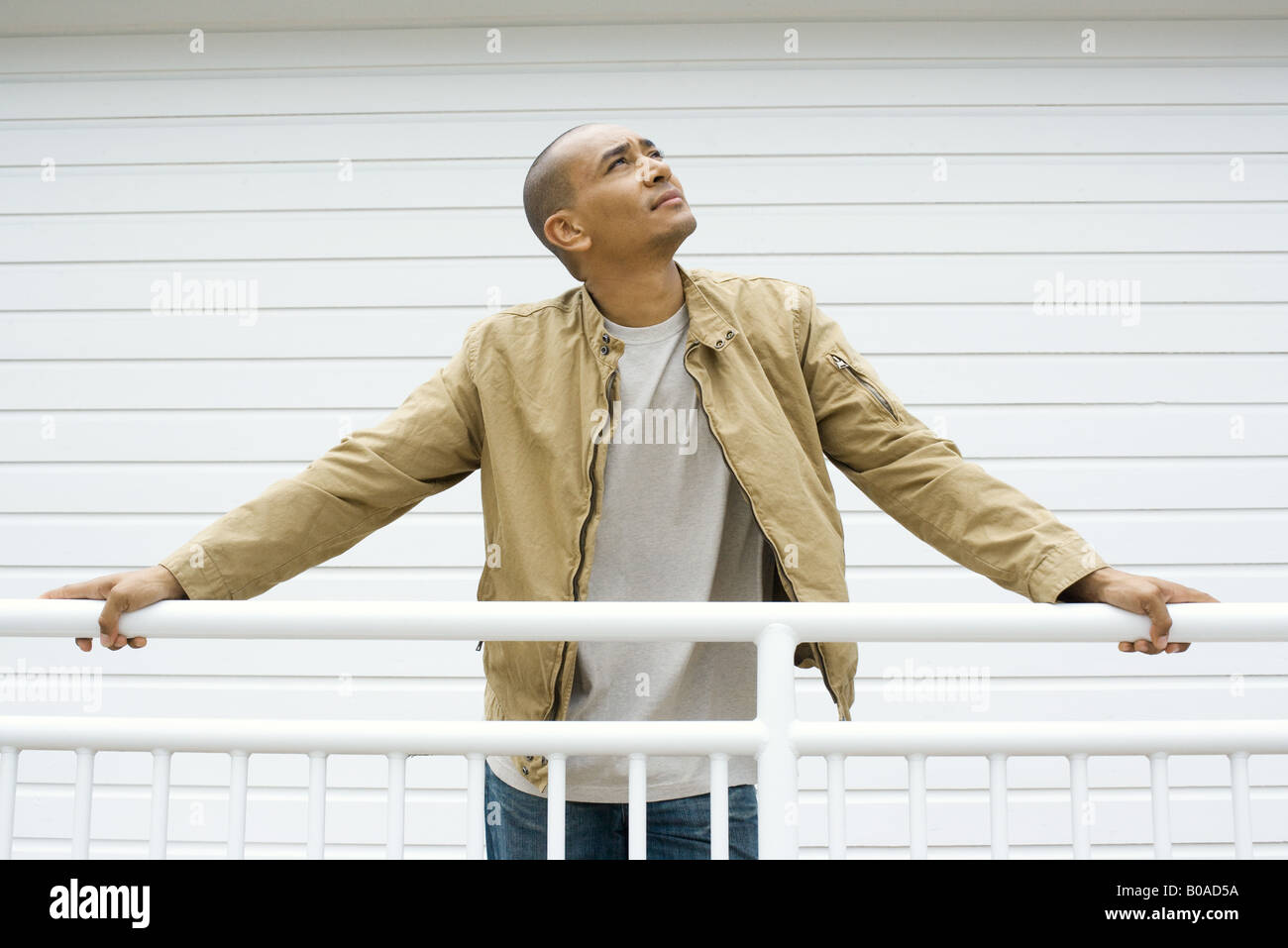 Man holding on to railing, looking up Stock Photo - Alamy