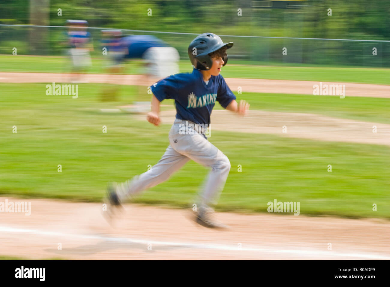 Young boy running from third base to home plate during a Little League ...