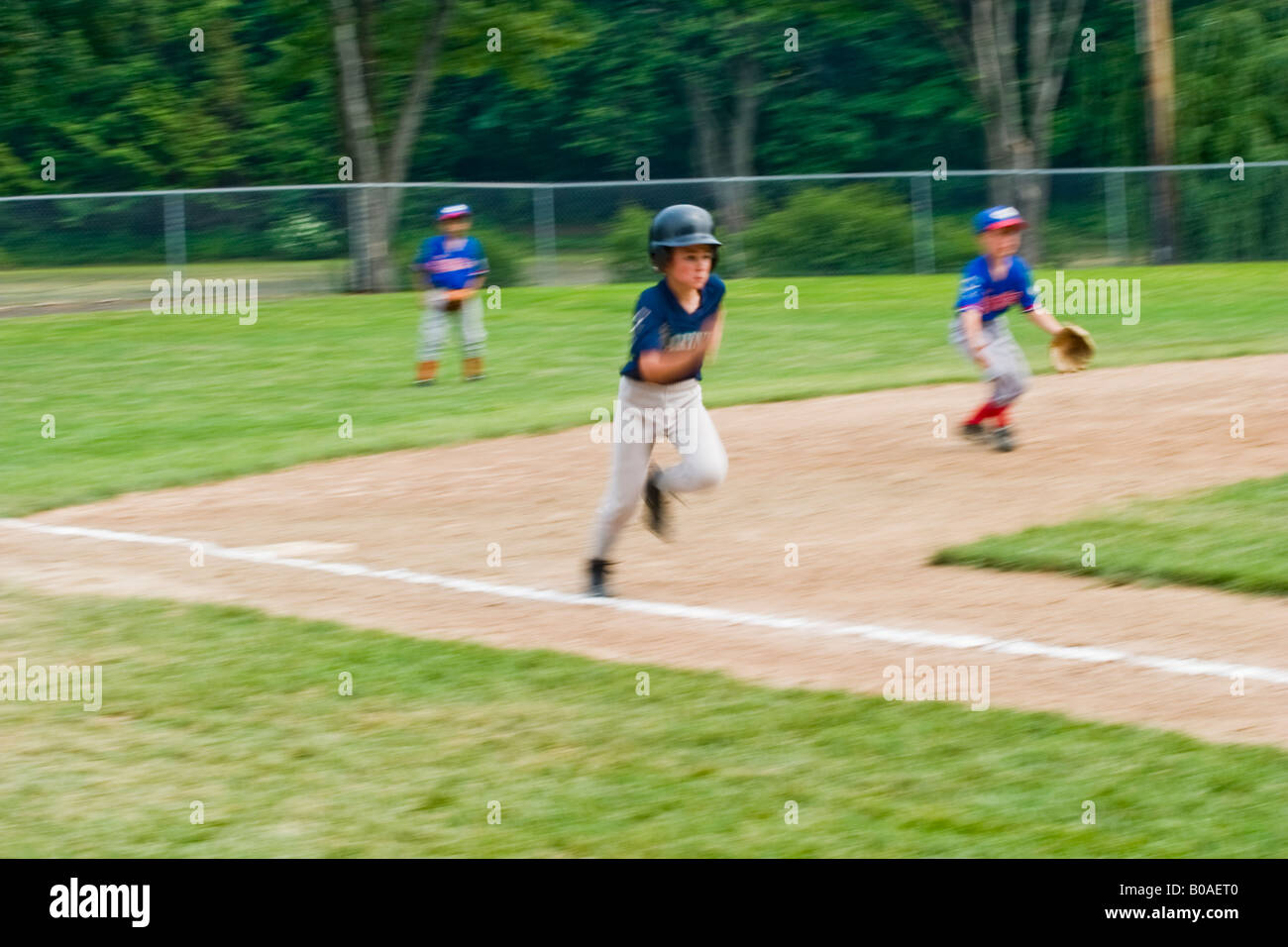 Young boy running from third base to home plate during a Little League ...