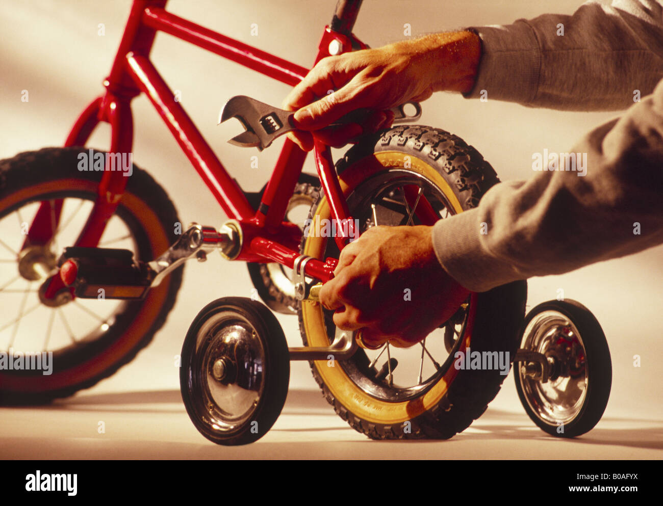 fixing training wheels on bicycle Stock Photo - Alamy
