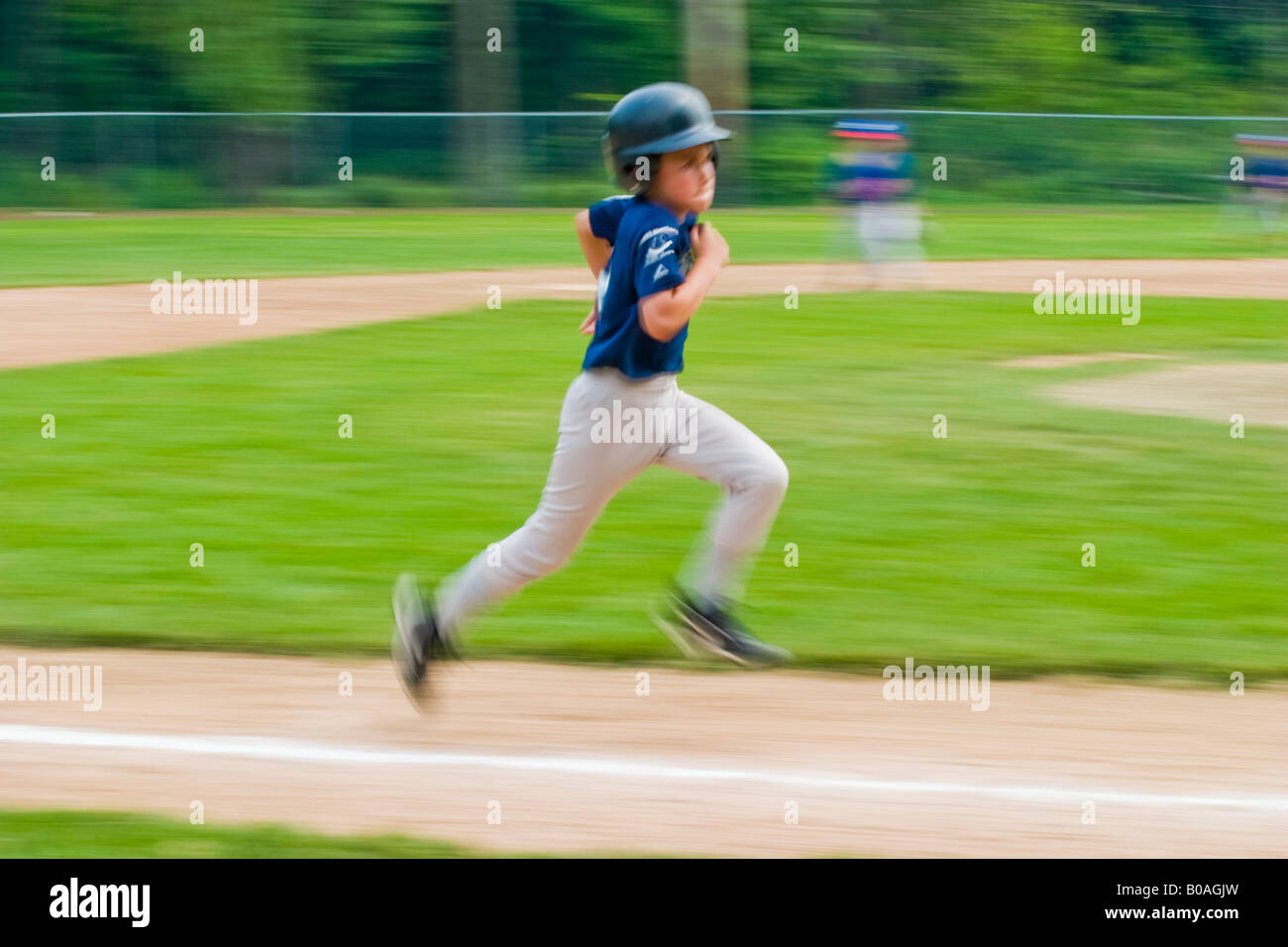 Young boy running from third base to home plate during a Little League ...