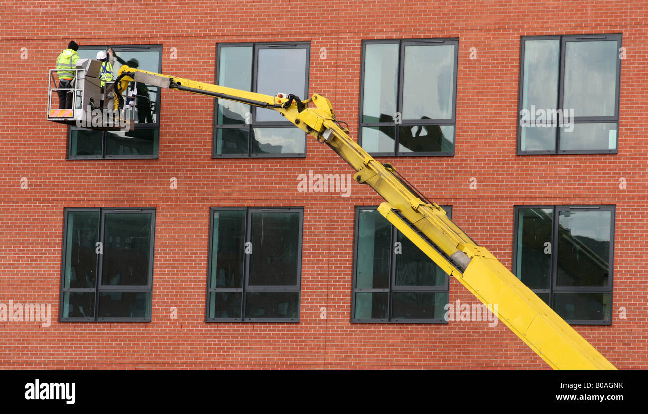 Two construction workers in a cherry picker doing finishing work on a ...