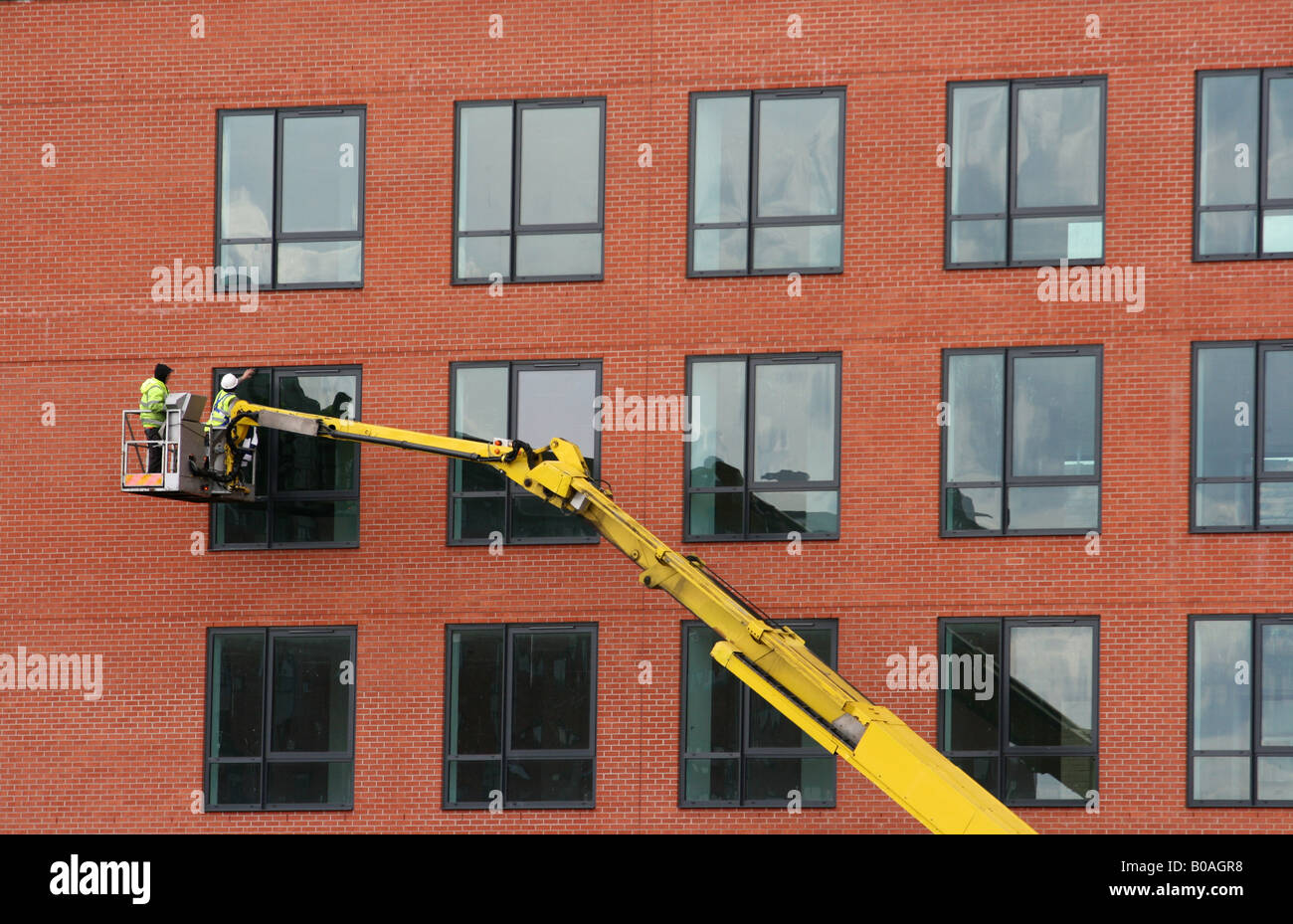 Two construction workers in a cherry picker doing finishing work on a ...