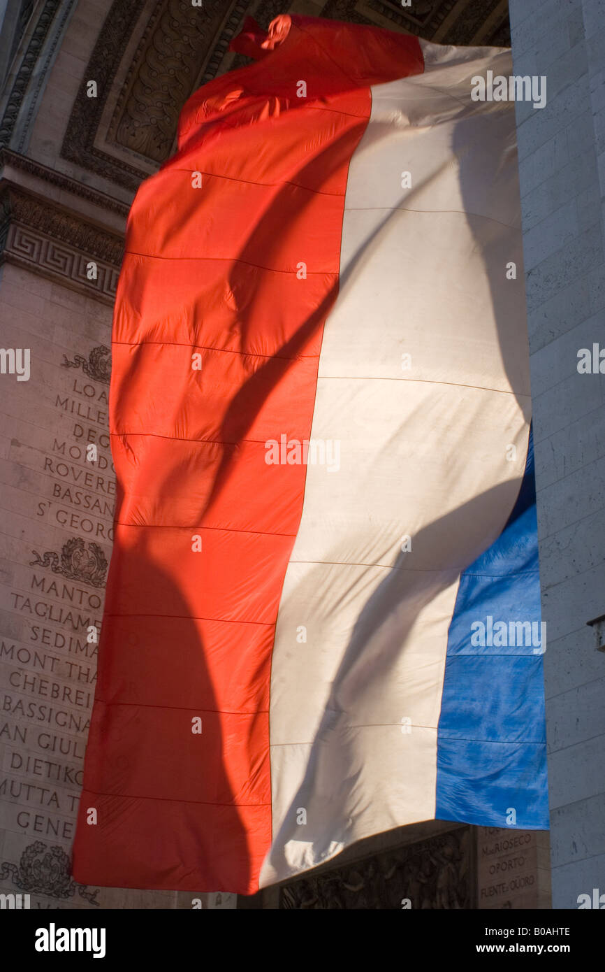 French tricolor flag flying in the setting sunlight underneath the Arc ...